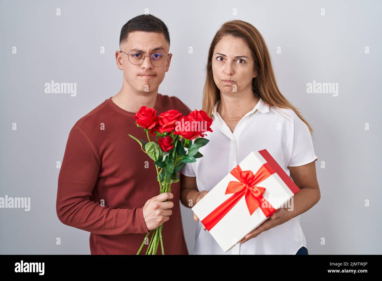 Mother and son holding mothers day gift skeptic and nervous, frowning ...