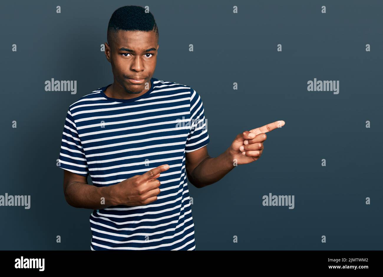 Young african american man pointing with fingers to the side depressed ...
