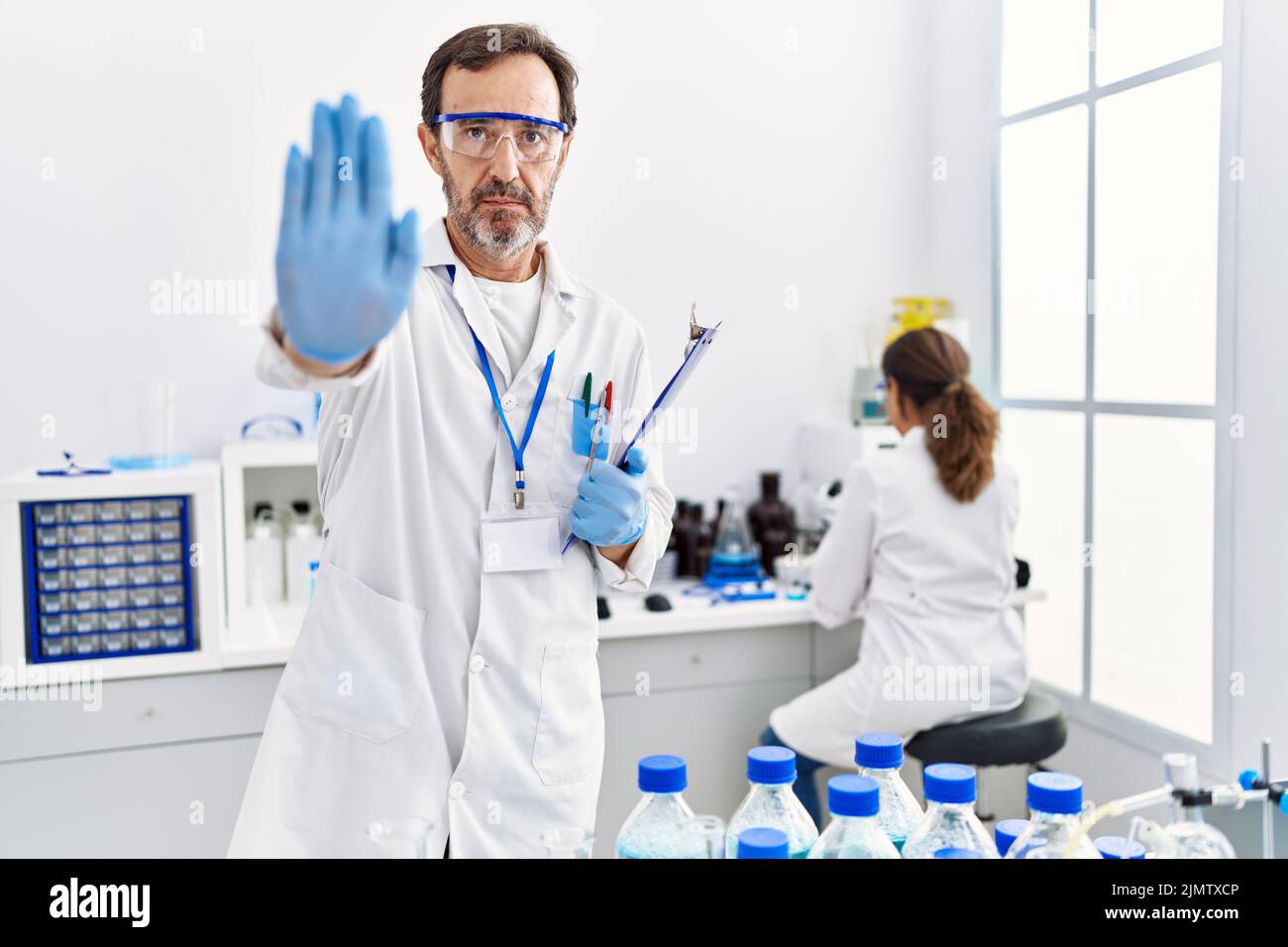 Middle age man working at scientist laboratory with open hand doing ...