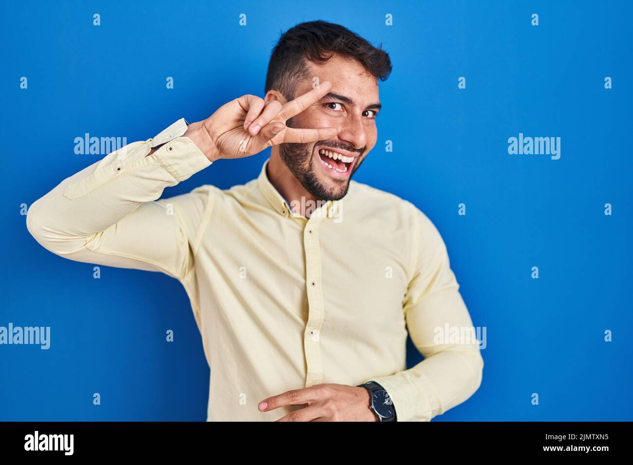 Handsome hispanic man standing over blue background doing peace symbol ...