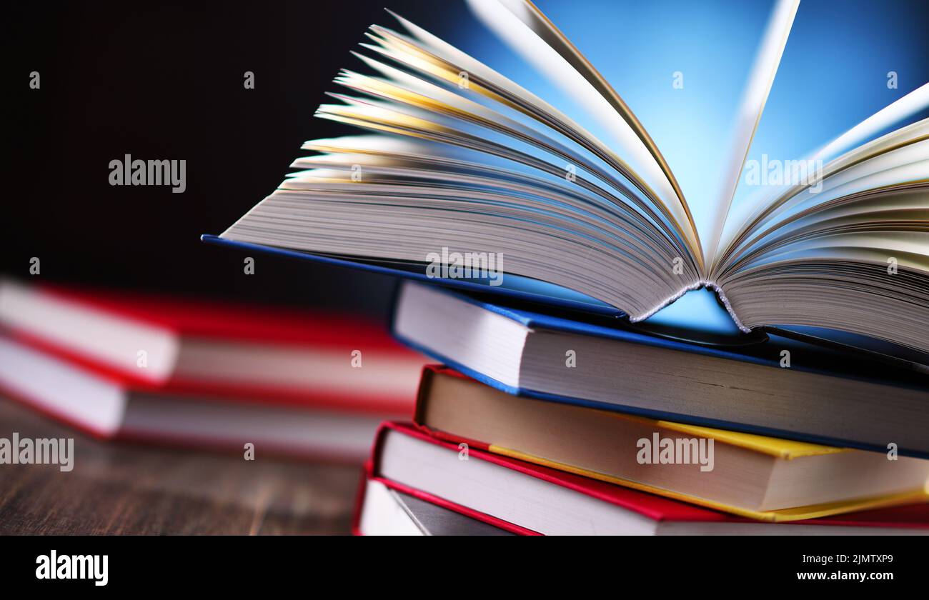 A composition with an open book lying on a stack of other books Stock ...