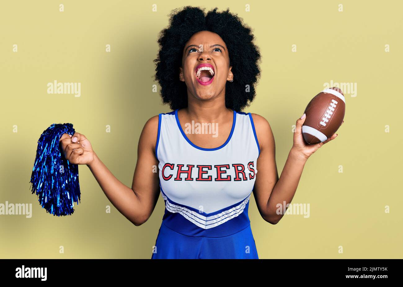 Young african american woman wearing cheerleader uniform holding pompom ...