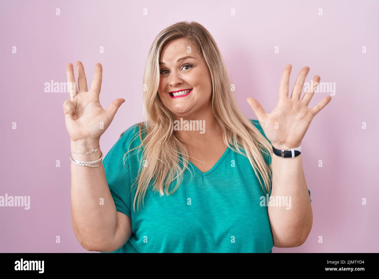 Caucasian plus size woman standing over pink background showing and ...