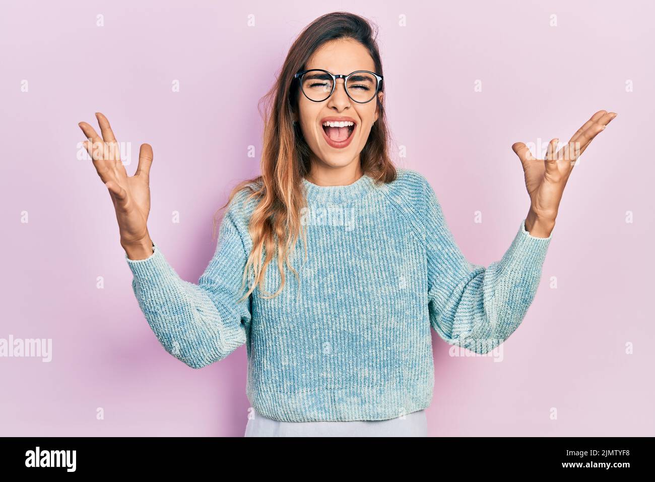 Young hispanic girl wearing casual clothes and glasses celebrating mad ...
