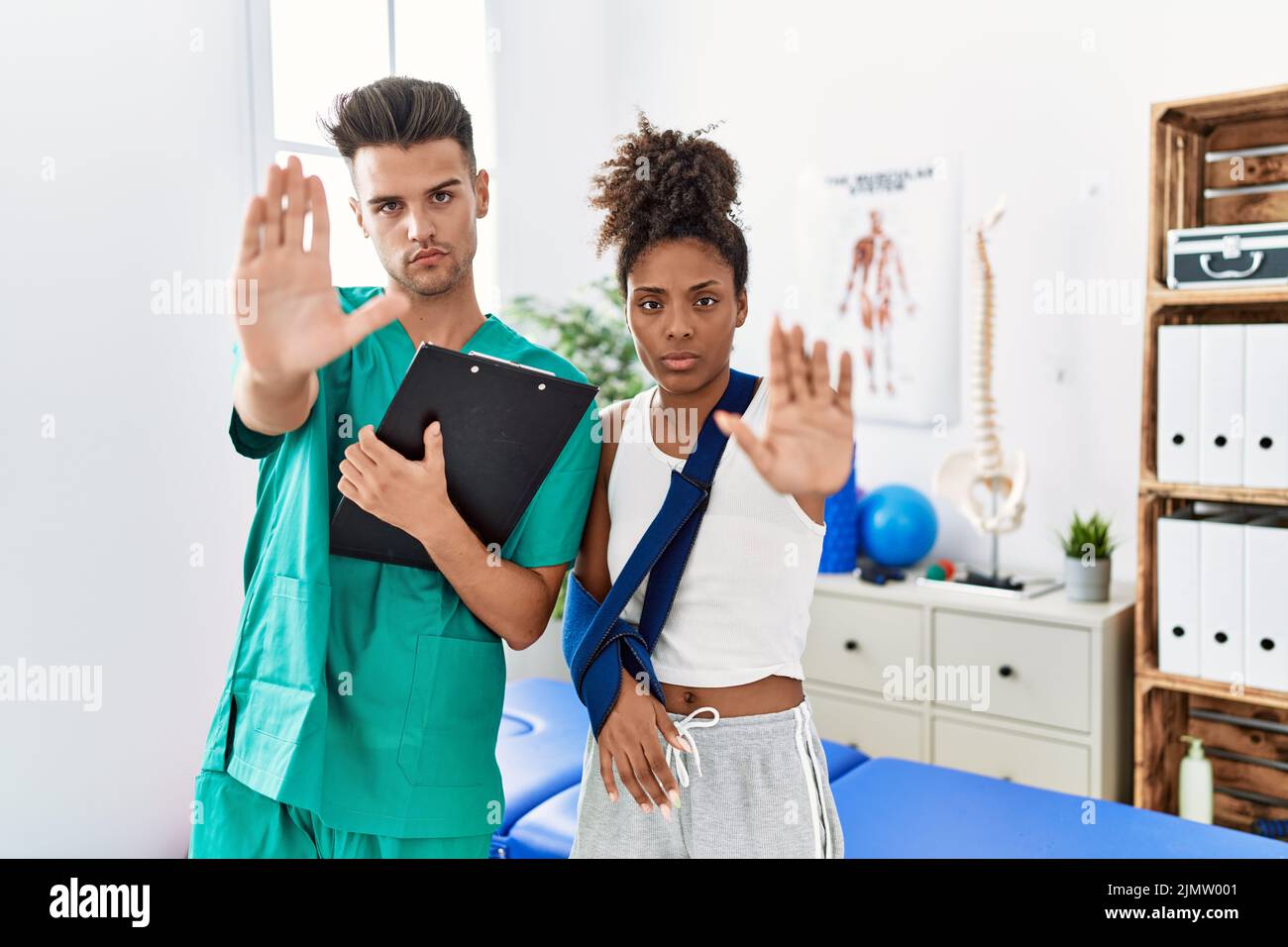 Physiotherapist working with patient wearing arm on sling at ...