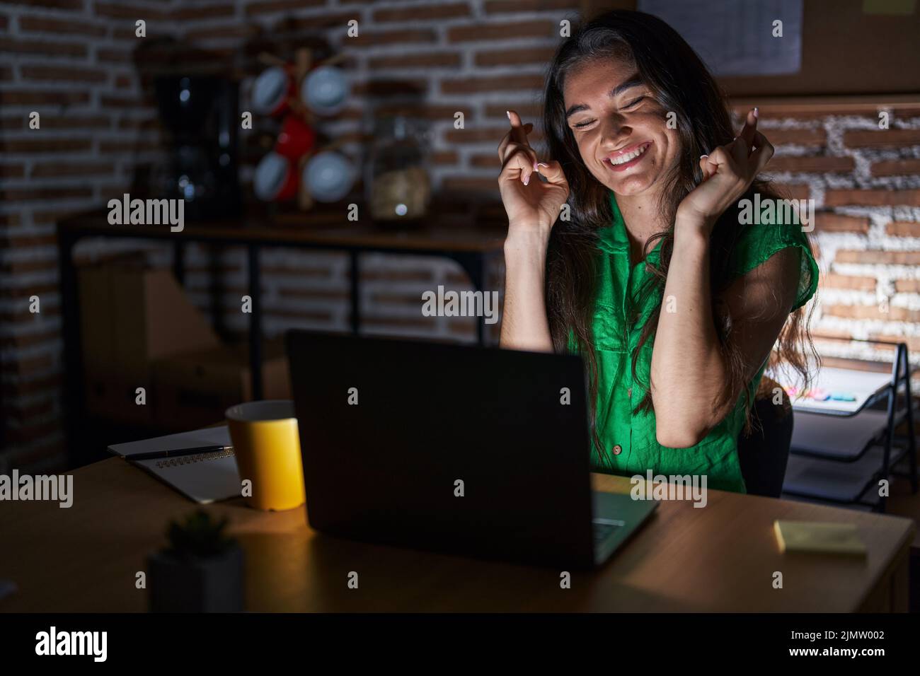 Young teenager girl working at the office at night gesturing finger ...