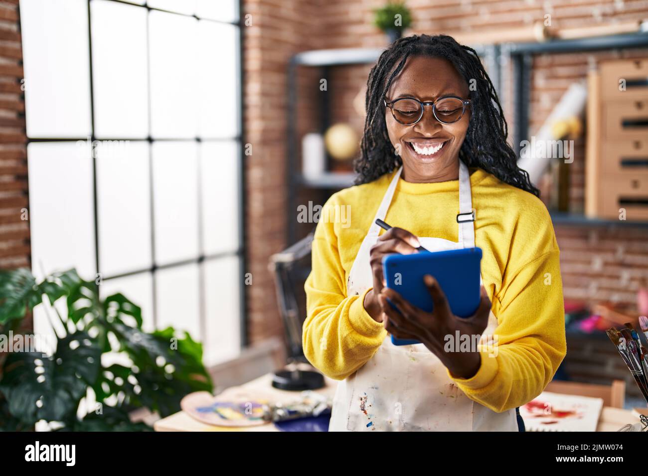 African american woman artist smiling confident using touchpad at art ...