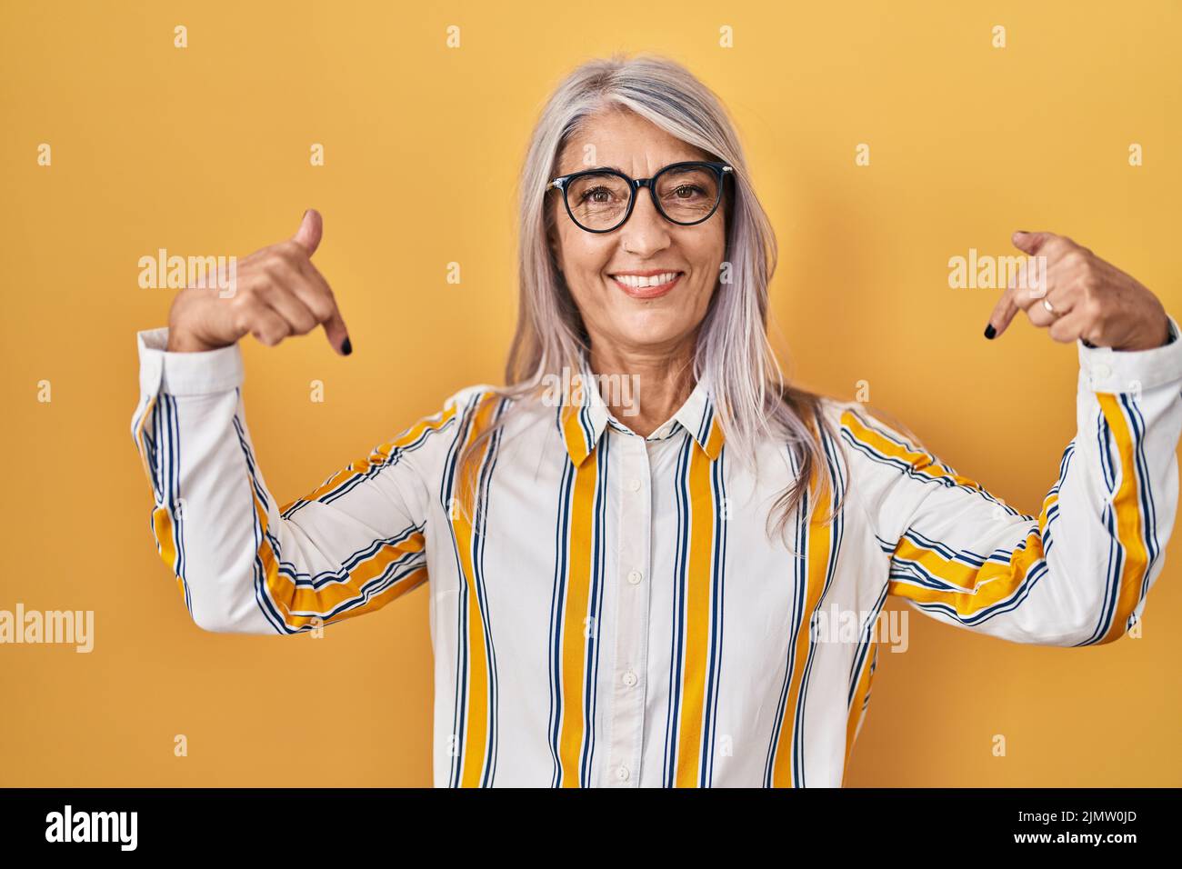 Middle age woman with grey hair standing over yellow background wearing ...