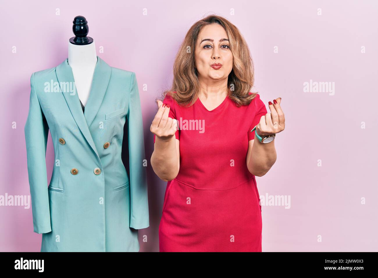 Middle age caucasian woman standing by manikin doing money gesture with ...