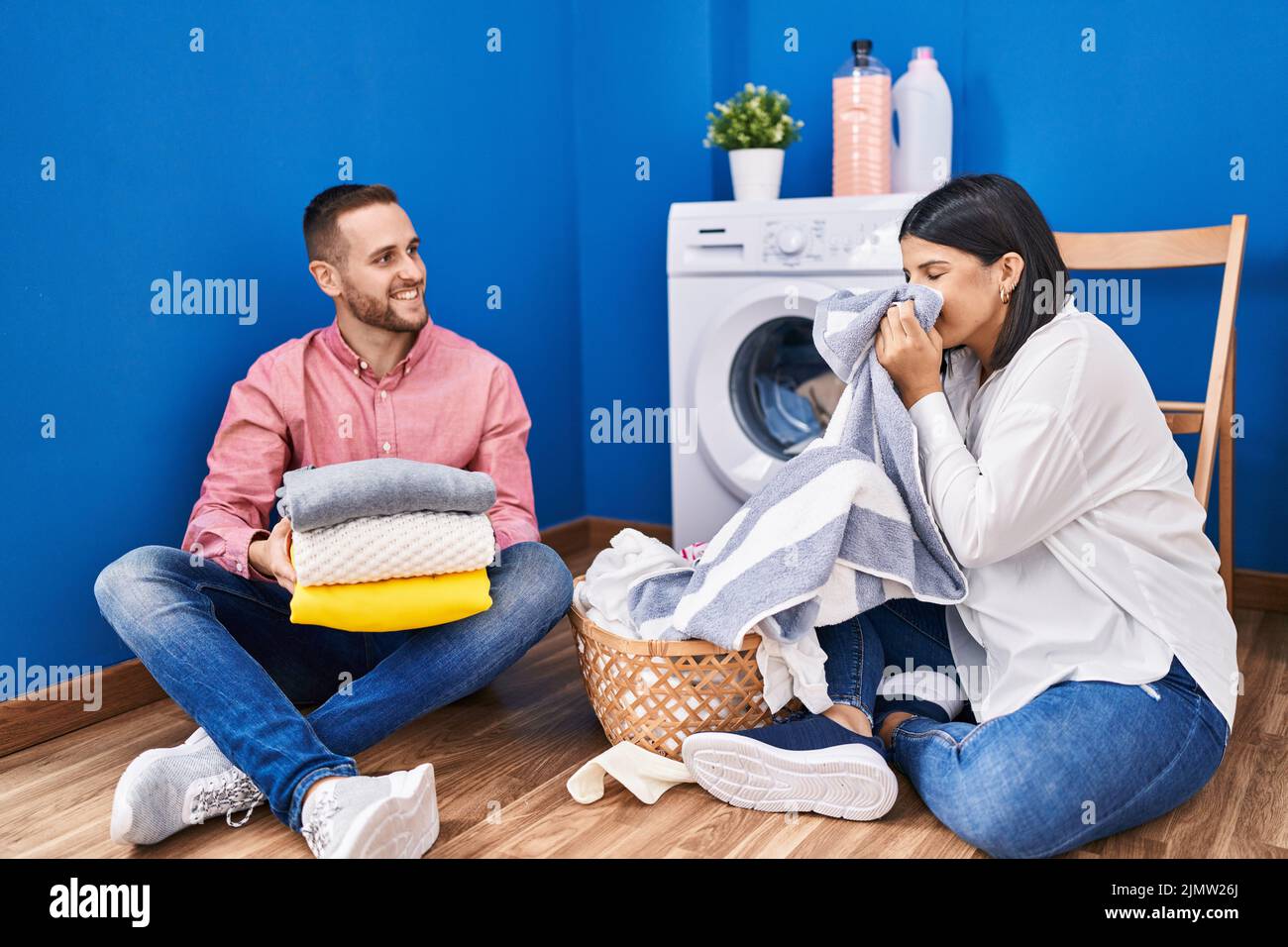 Man and woman couple washing and smelling clothes at laundry room Stock ...