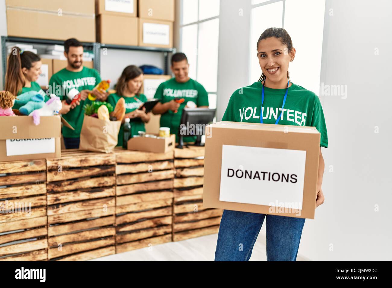 Group of young volunteers working at charity center. Woman smiling ...