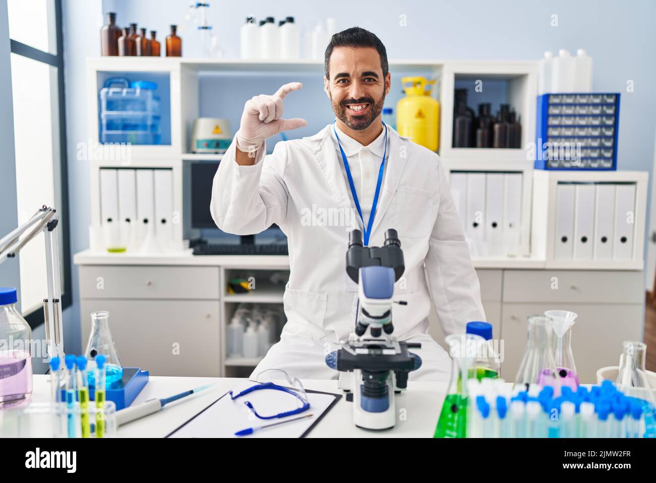 Young hispanic man with beard working at scientist laboratory smiling ...