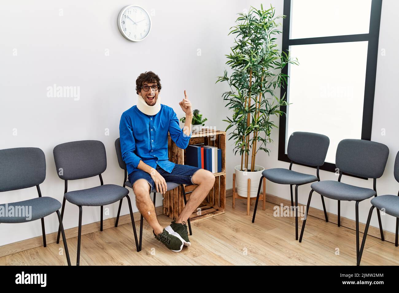 Young hispanic man sitting at doctor waiting room with neck injury ...