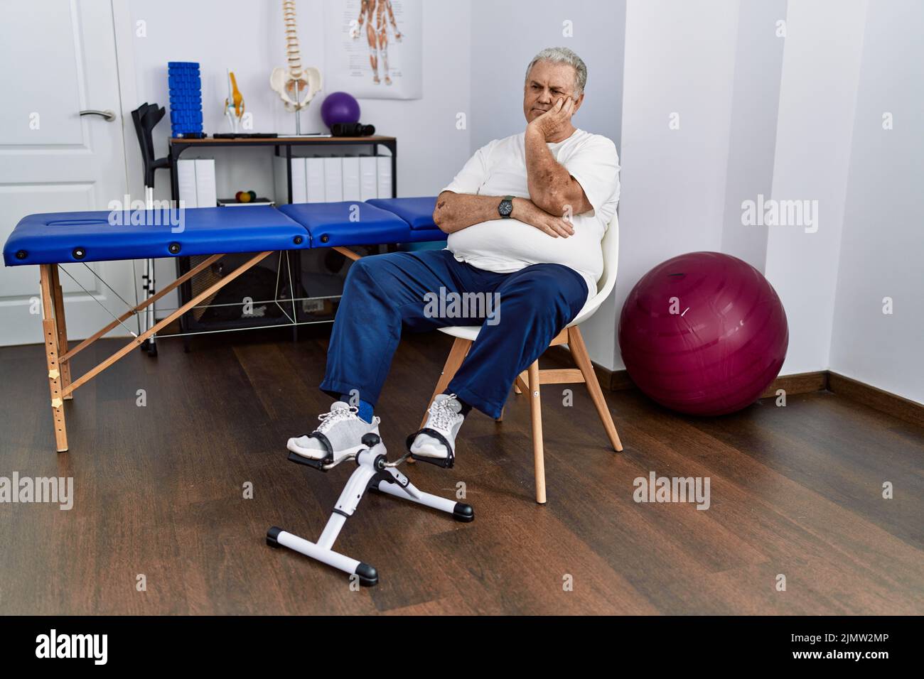 Senior caucasian man at physiotherapy clinic using pedal exerciser ...