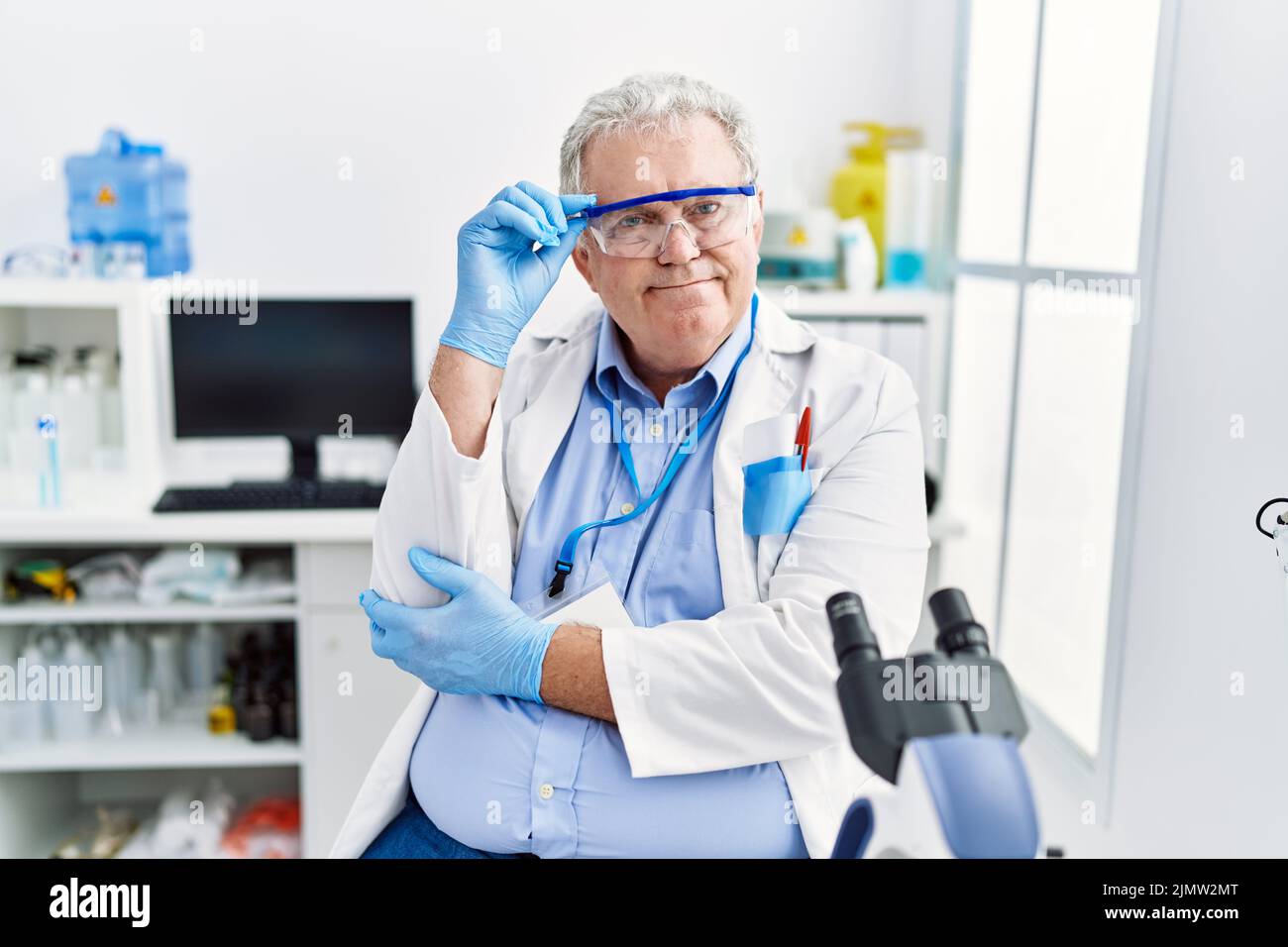 Middle age grey-haired man wearing scientist uniform with arms crossed ...