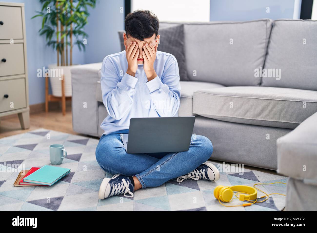 Non binary person studying using computer laptop sitting on the floor ...