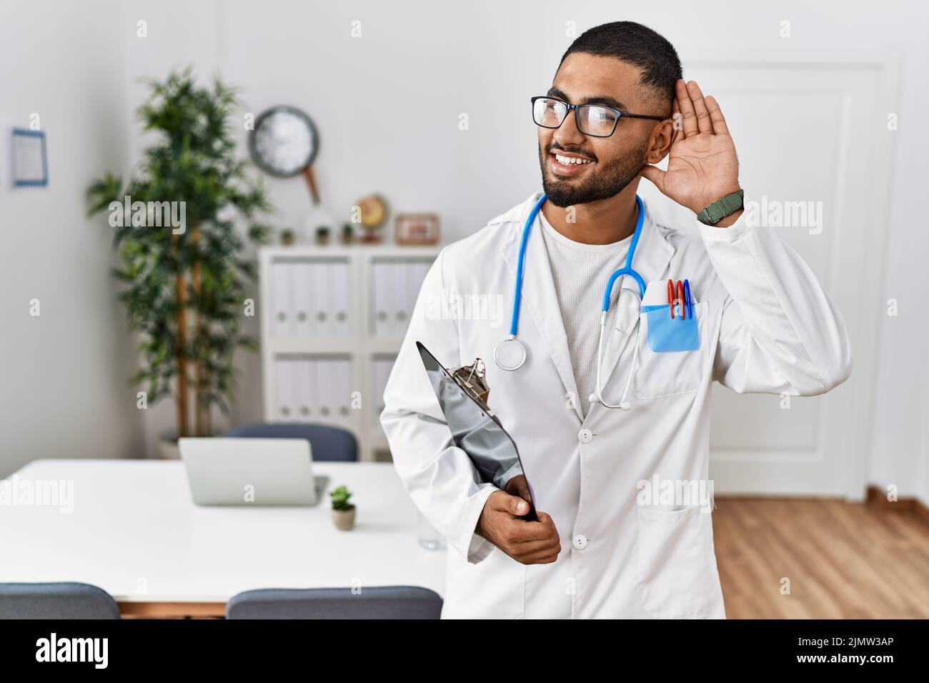 Young indian man wearing doctor uniform and stethoscope smiling with ...