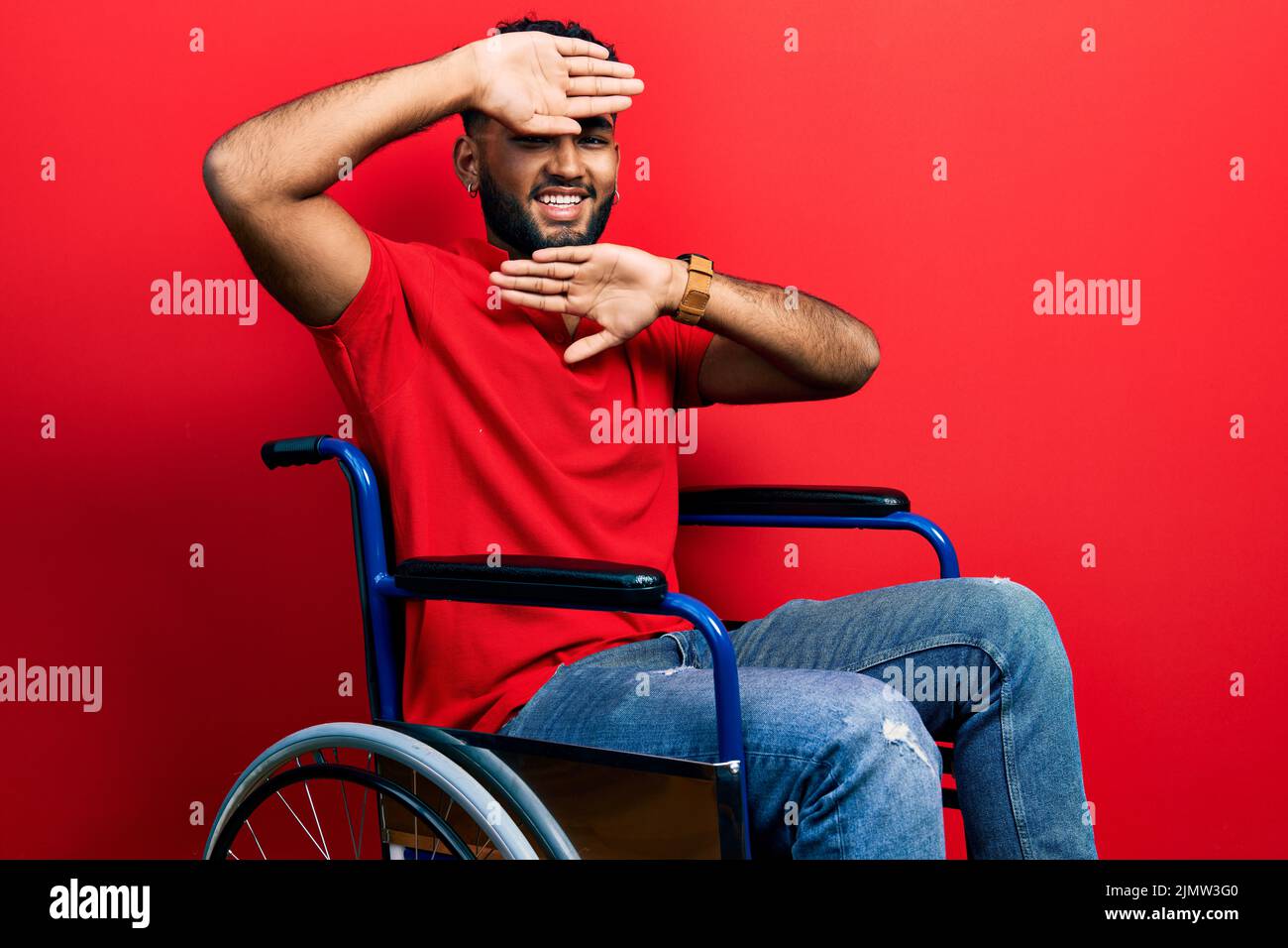 Arab man with beard sitting on wheelchair smiling cheerful playing peek ...