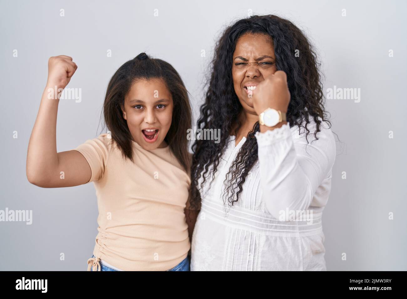 Mother and young daughter standing over white background angry and mad ...