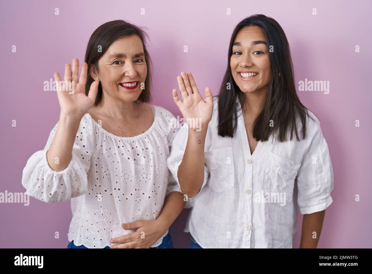 Hispanic mother and daughter together waiving saying hello happy and ...