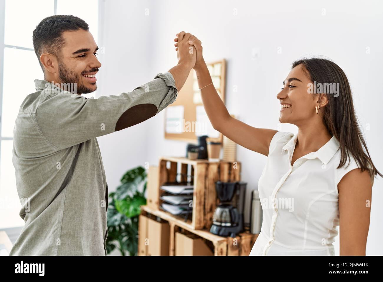 Two latin business workers smiling happy high five with hands raised up ...