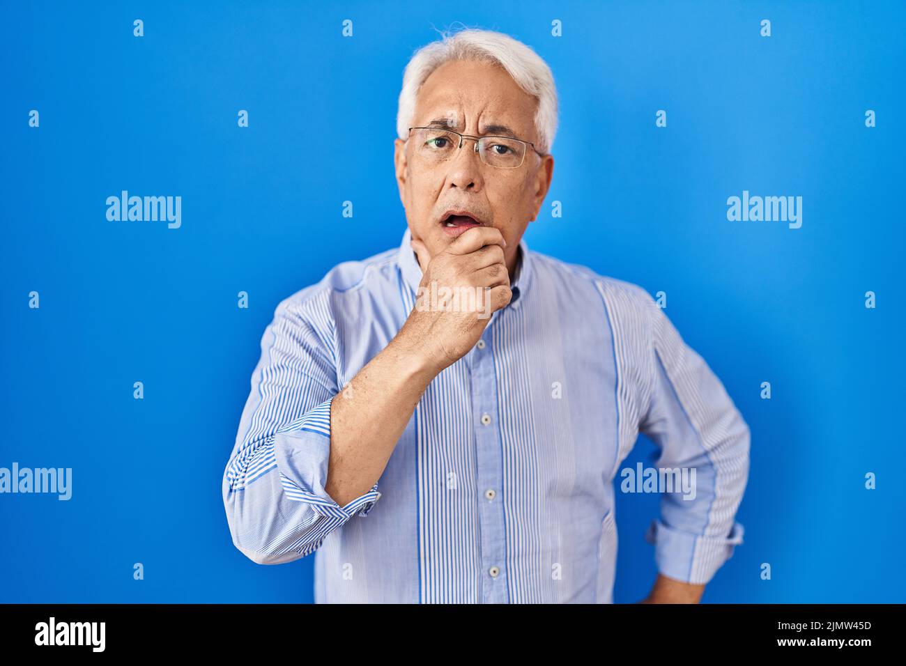 Hispanic senior man wearing glasses looking fascinated with disbelief ...