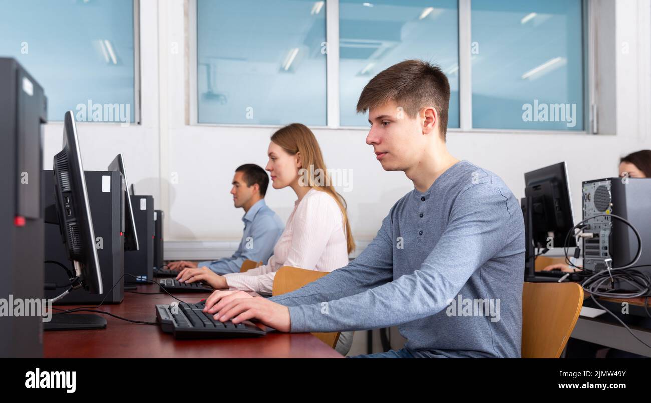 Side view of focused female and male students working on computers in ...