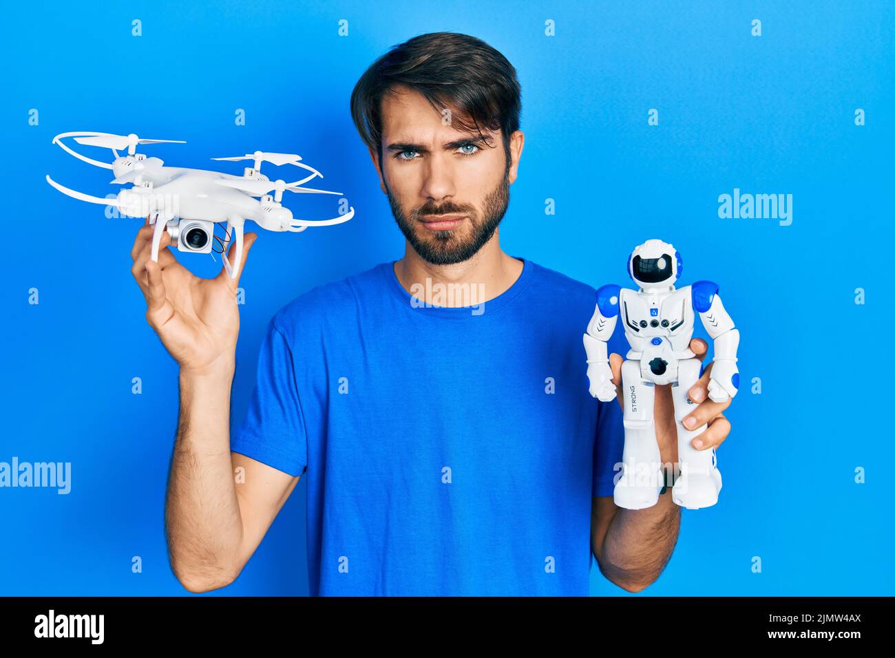 Young hispanic man holding drone and robot toy depressed and worry for ...