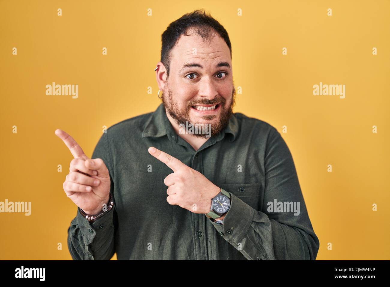 Plus size hispanic man with beard standing over yellow background ...