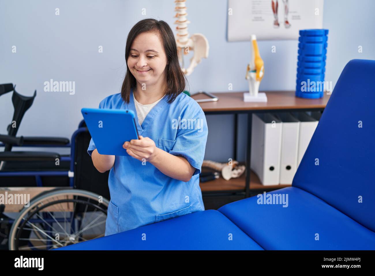 Down syndrome woman wearing physiotherapy uniform using touchpad at ...
