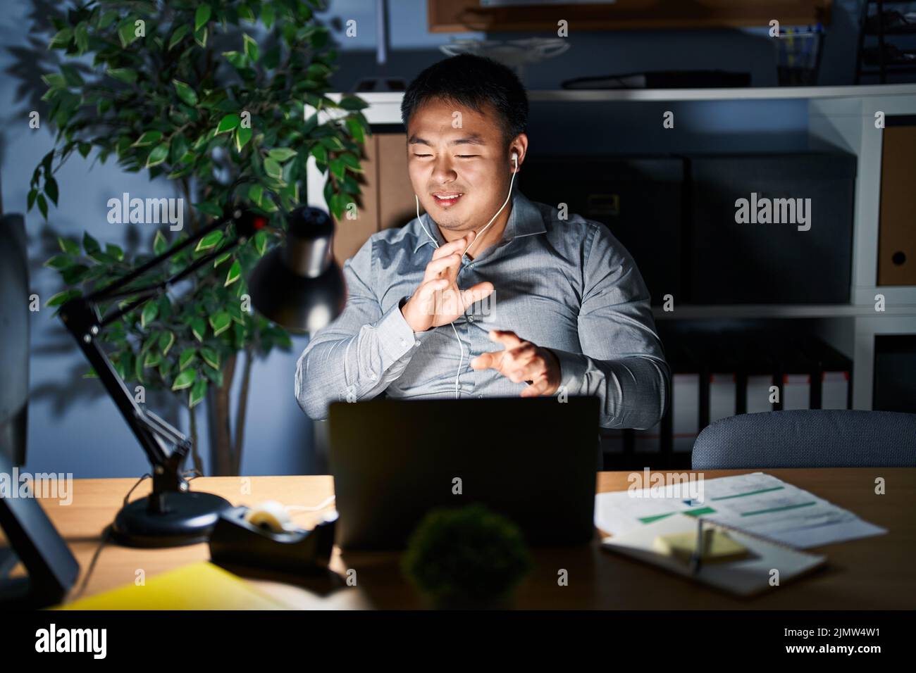 Young chinese man working using computer laptop at night disgusted ...