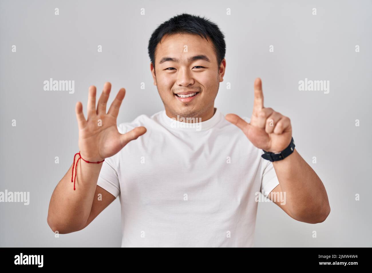 Young chinese man standing over white background showing and pointing ...