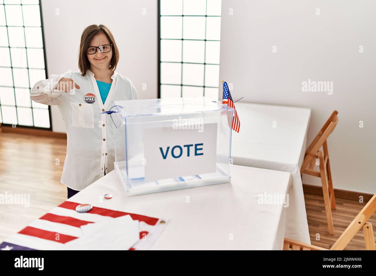 Brunette woman with down syndrome smiling showing vote badge at ...
