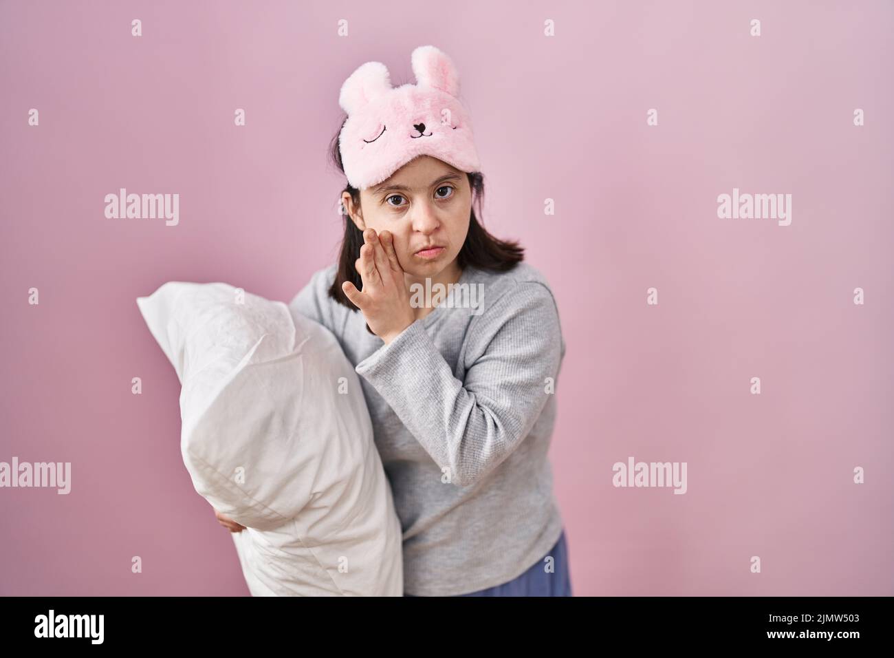 Woman with down syndrome wearing sleeping mask hugging pillow hand on ...