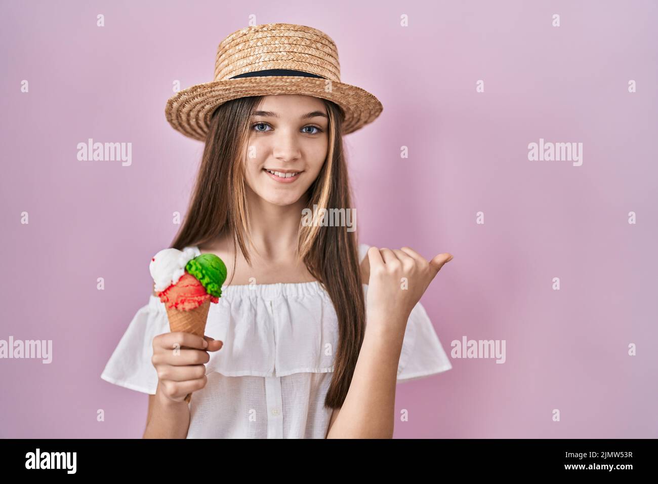 Teenager girl holding ice cream pointing to the back behind with hand ...