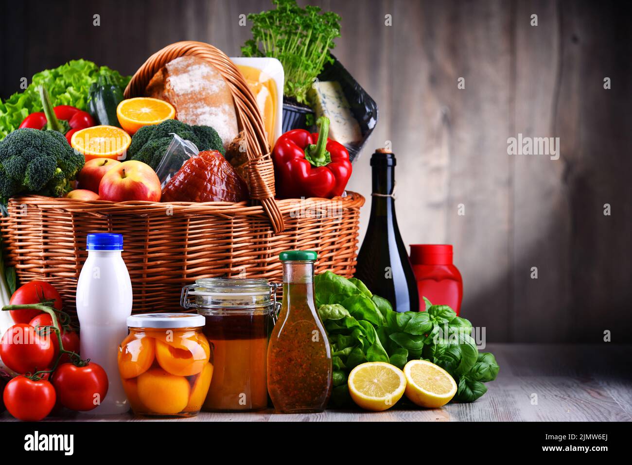 Wicker basket with assorted grocery products including fresh vegetables ...