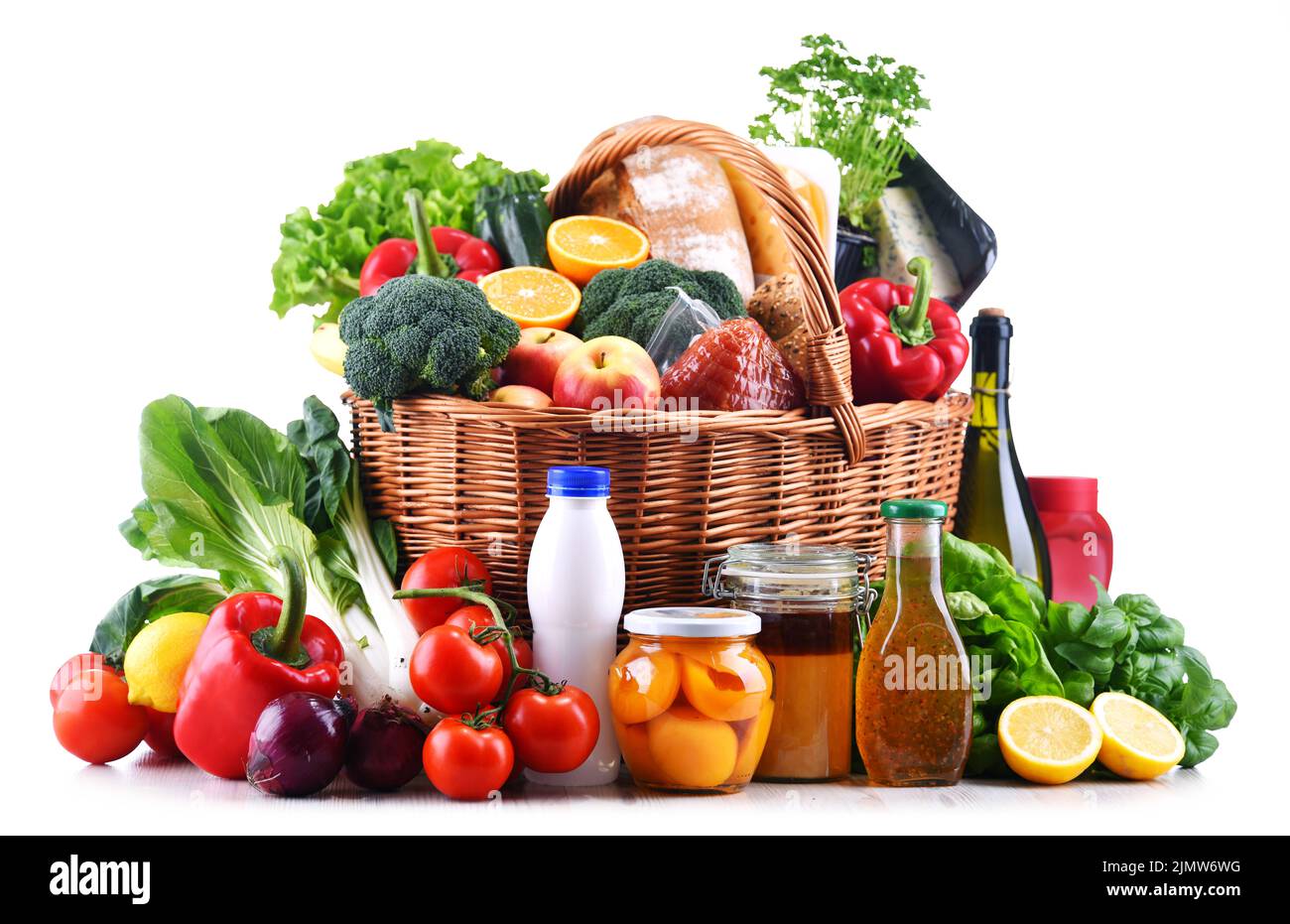 Wicker basket with assorted grocery products including fresh vegetables ...