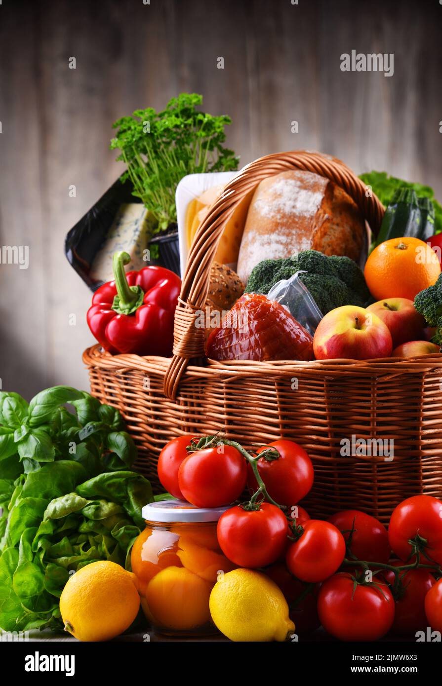 Wicker basket with assorted grocery products including fresh vegetables ...