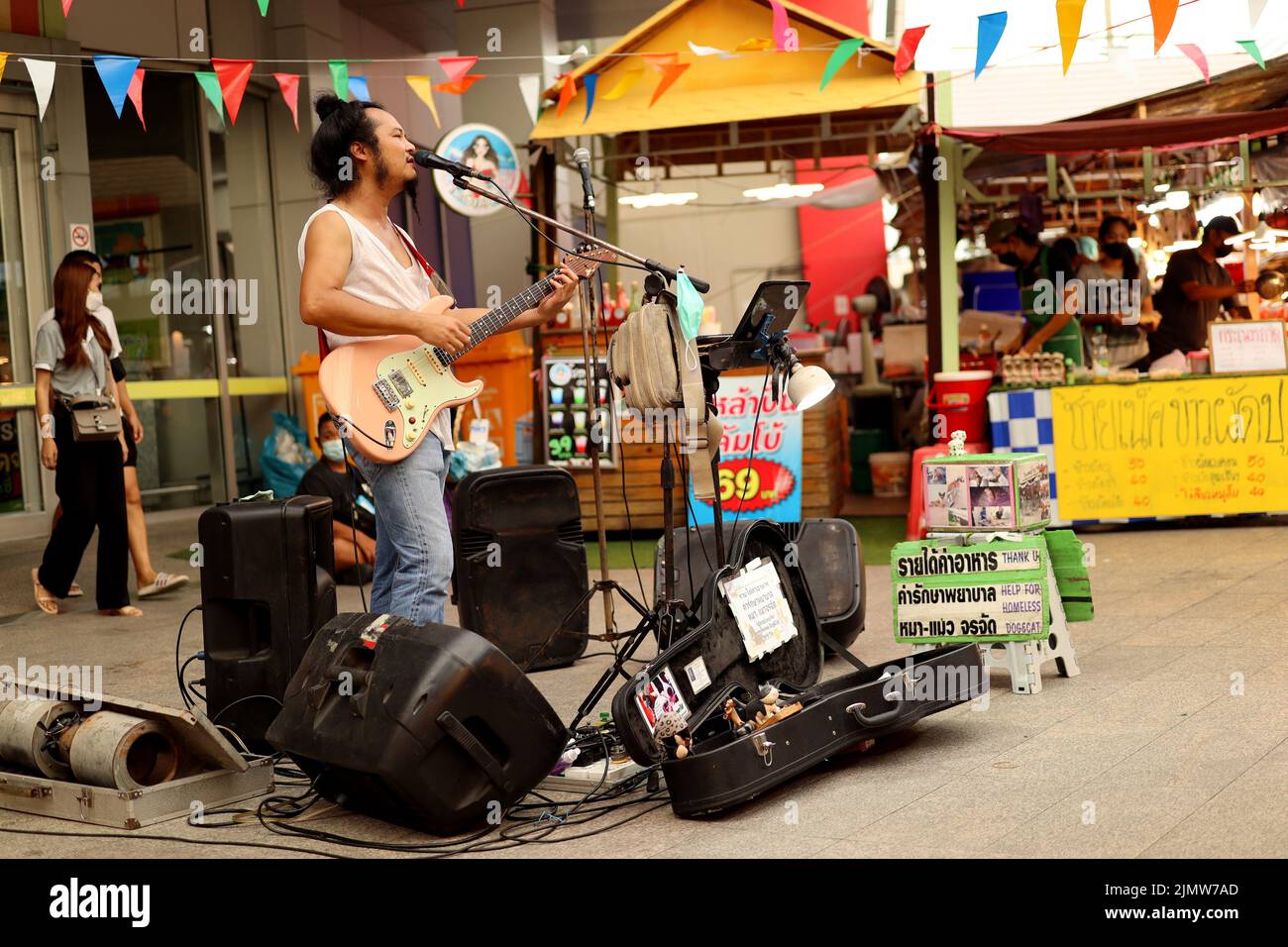 A male street musician playing an electric guitar and singing in ...