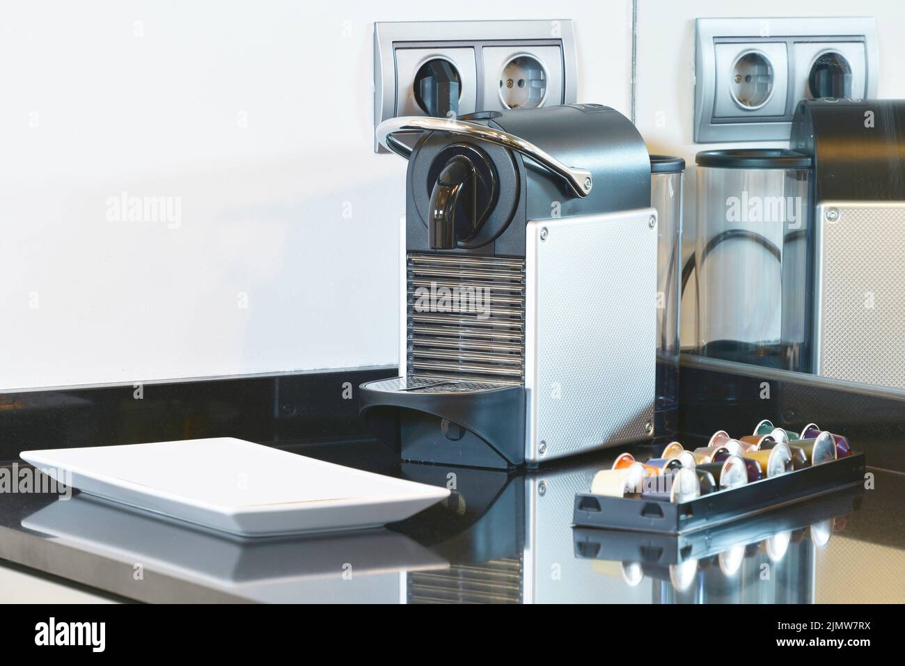 Corner of a black stone countertop in a kitchen with a pod coffee ...