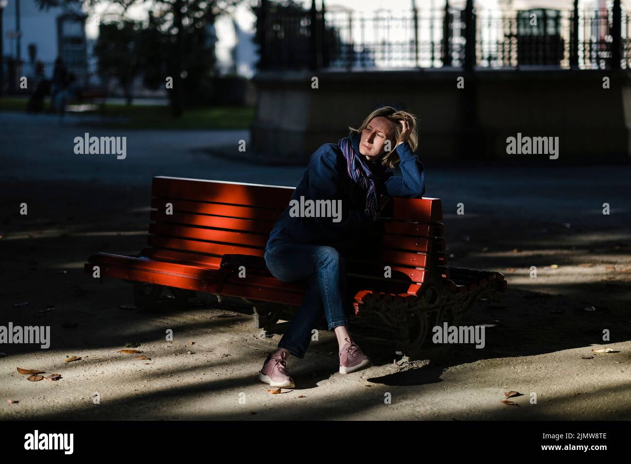A woman sits sadly on a park bench Stock Photo - Alamy
