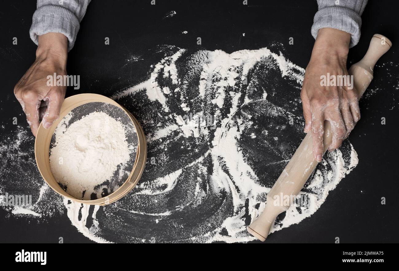 Female hands hold a round wooden sieve with white wheat flour on a ...