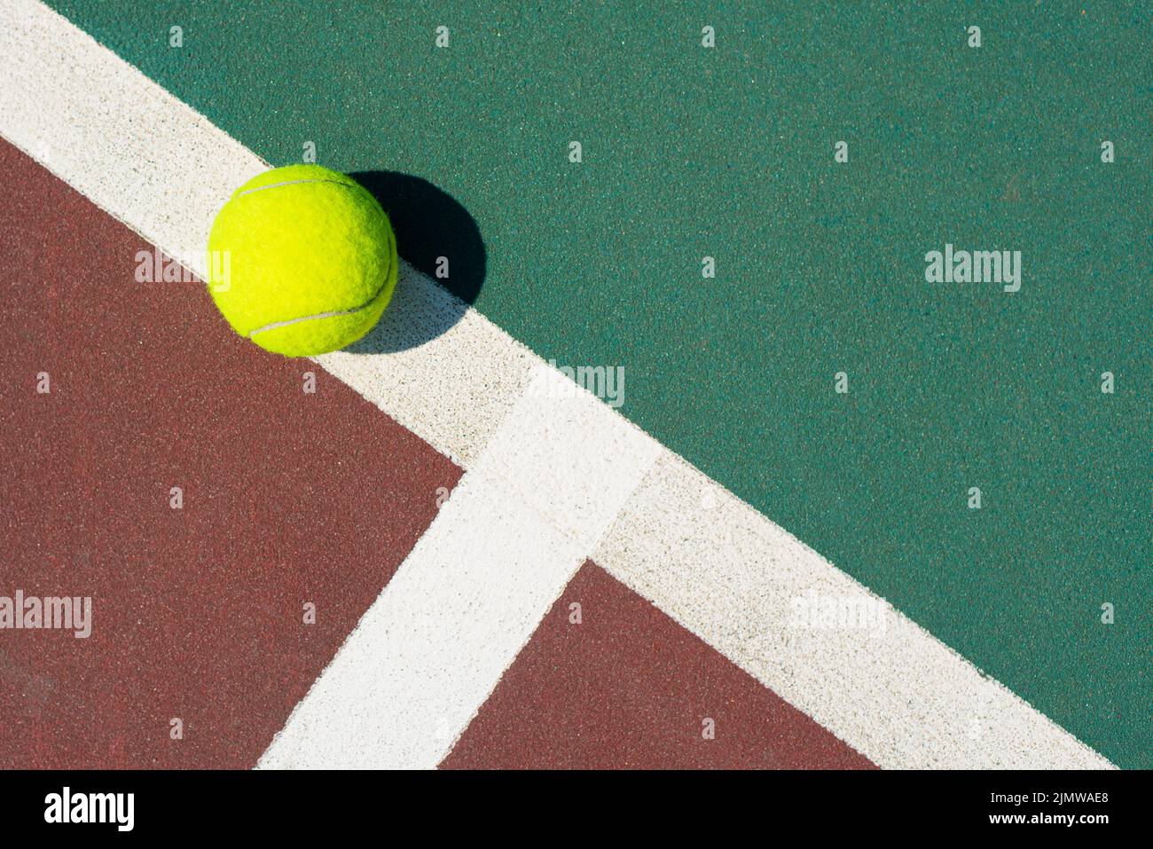 Yellow tennis ball lying on line of the red and green court. Flat lay ...