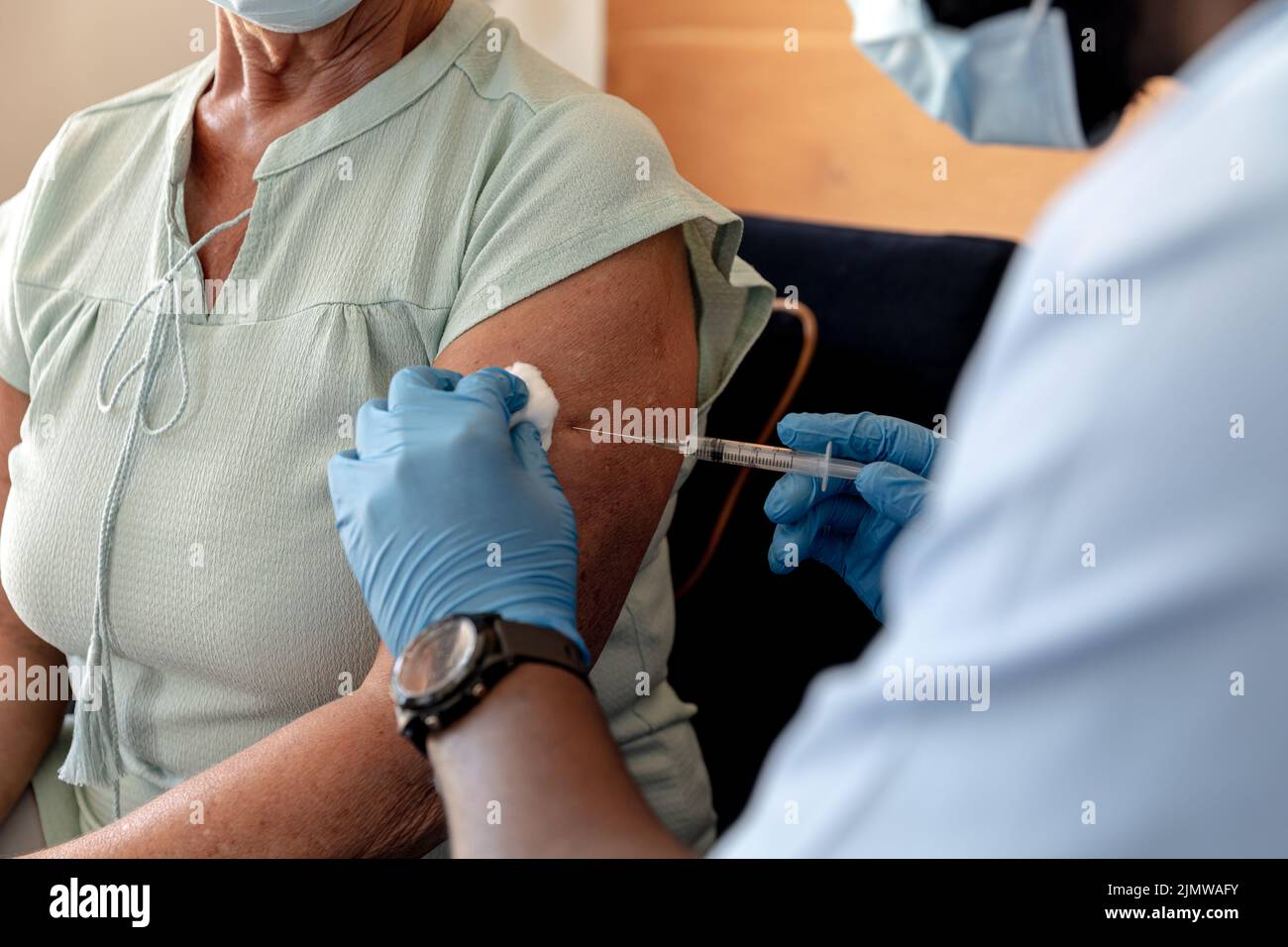 Mid section of african american male health worker giving an injection ...