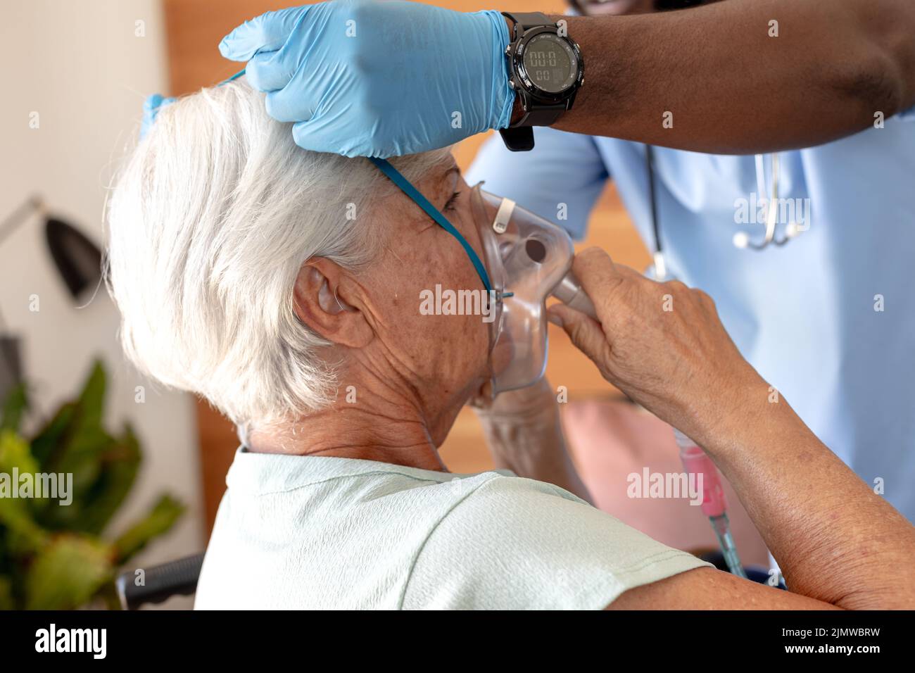 Mid section of male health worker putting oxygen mask on caucasian senior woman on wheelchair ...