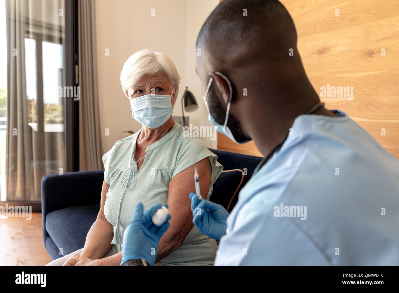 African american male health worker holding a syringe talking to ...