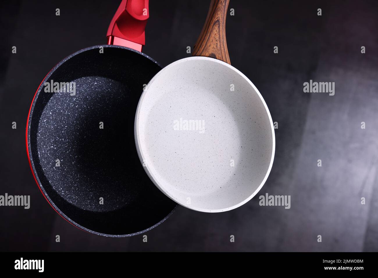 Two hanging stainless frying pans. Kitchen utensils Stock Photo - Alamy