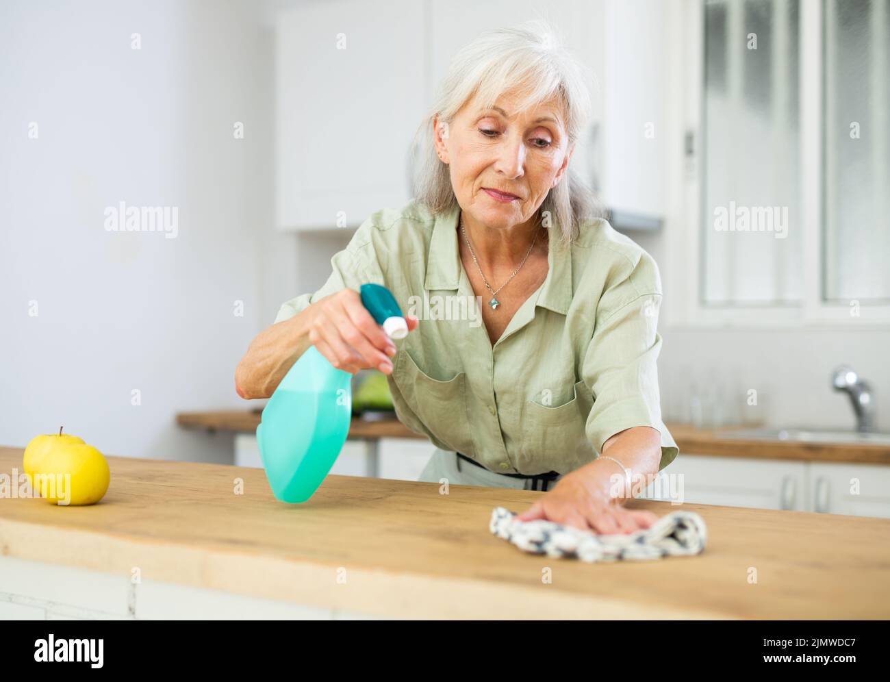 Old woman cleaning table with rag at home Stock Photo - Alamy