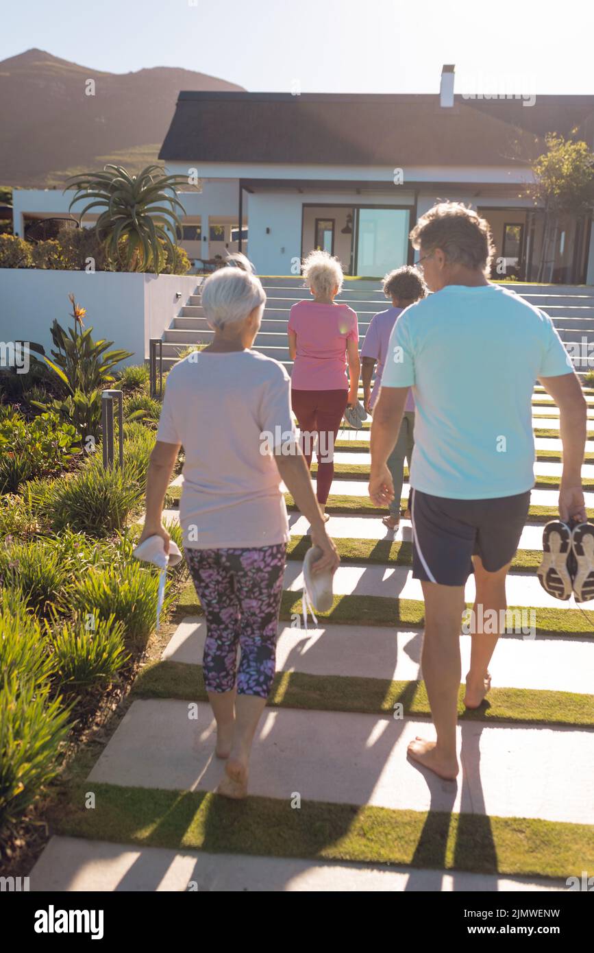 Rear view of multiracial senior man with women walking on steps towards ...