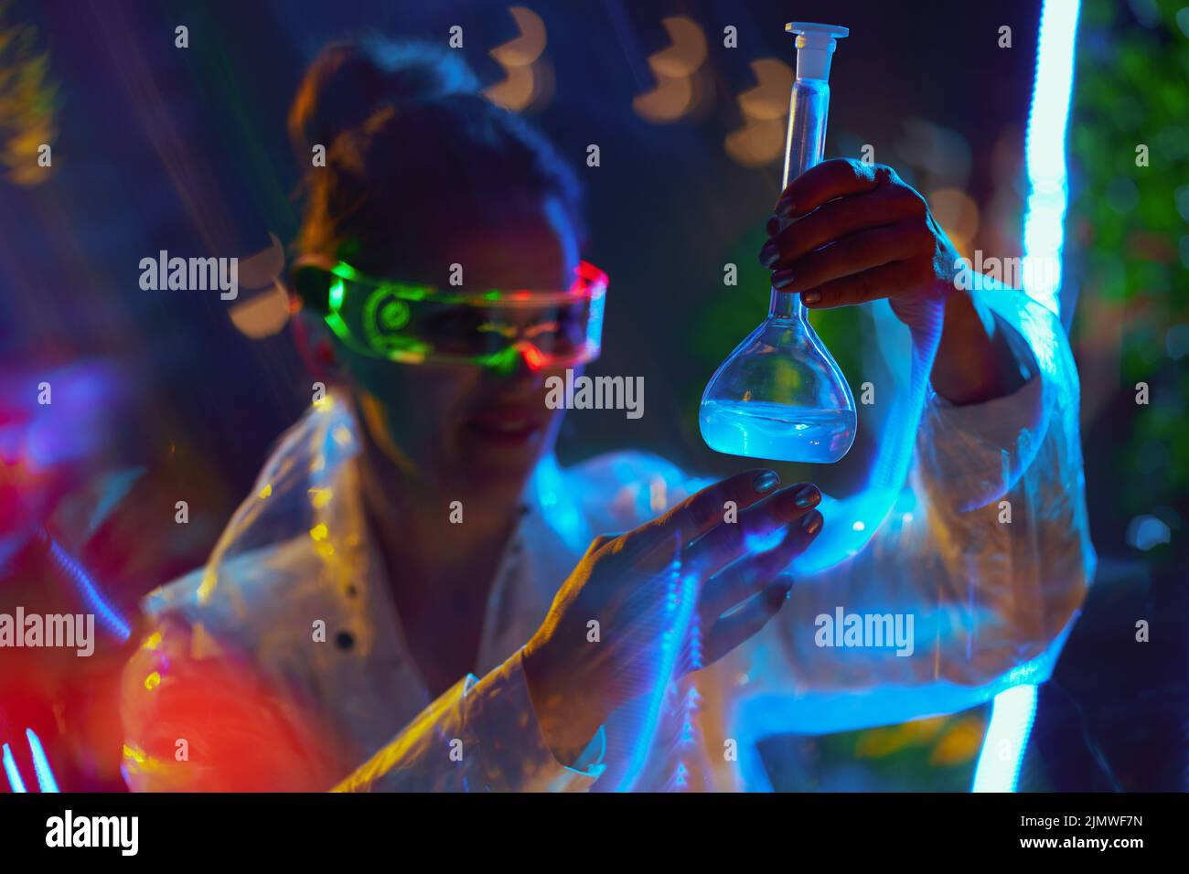 Closeup on scientist woman in lab coat with flask and futuristic ...